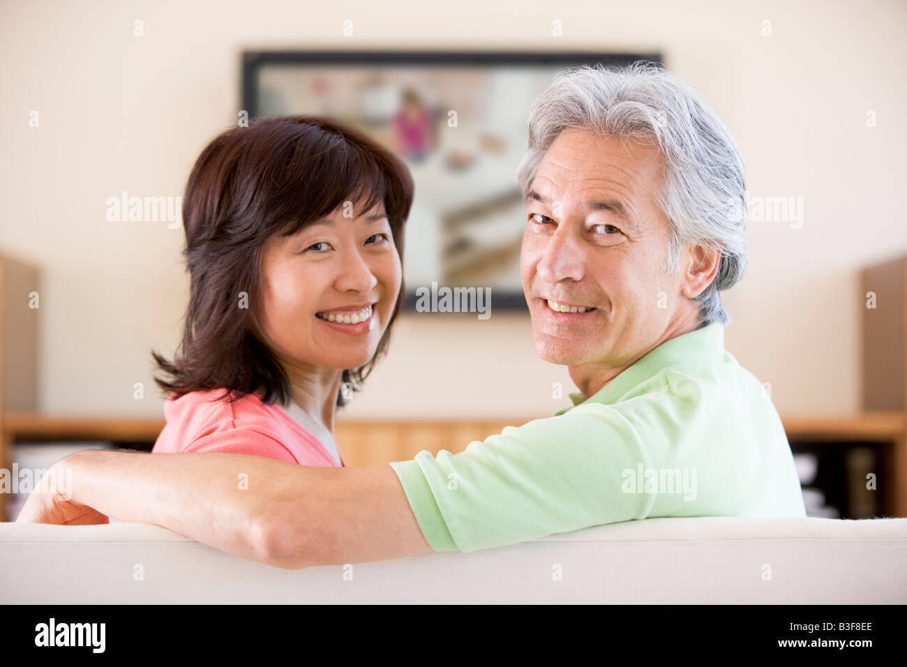 Couple watching television smiling Stock Photo - Alamy
