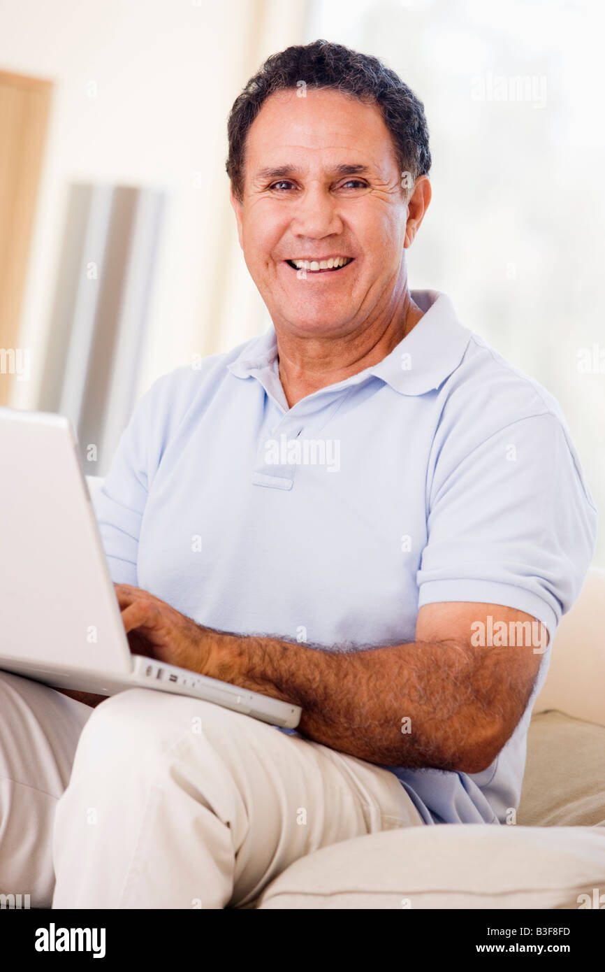 Man in living room with laptop smiling Stock Photo - Alamy