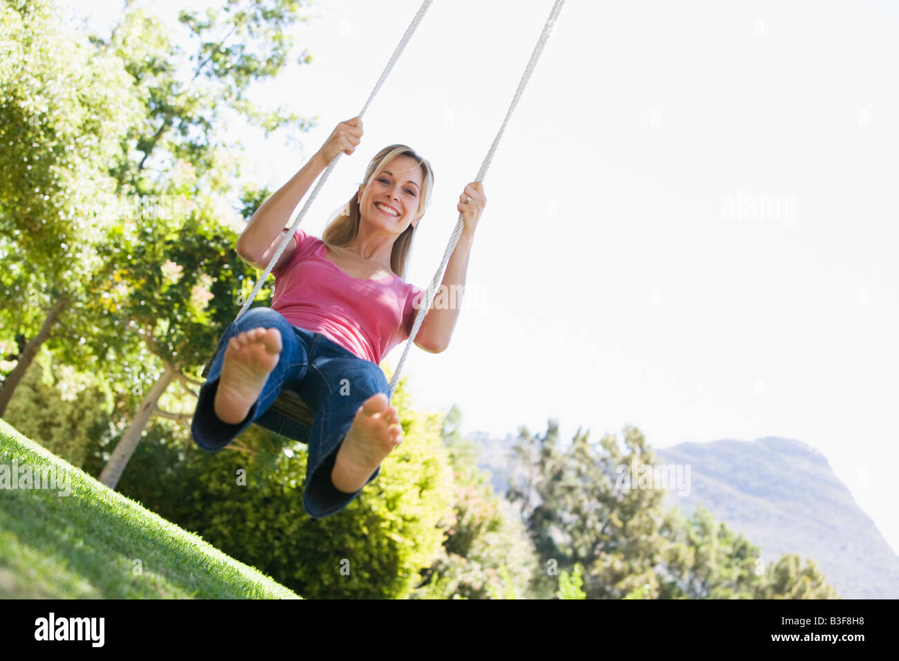 Woman on tree swing smiling Stock Photo - Alamy