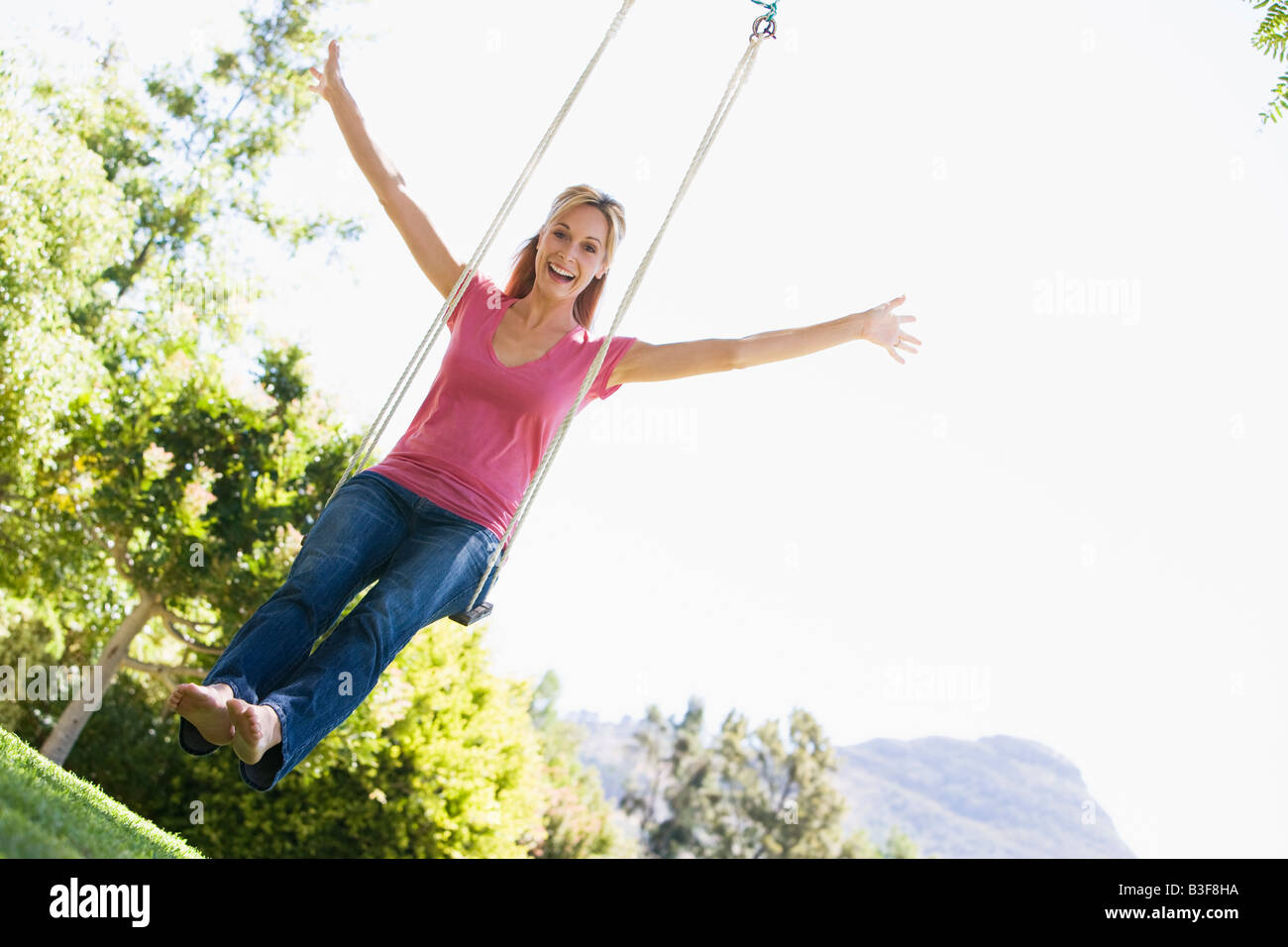 Woman on tree swing smiling Stock Photo - Alamy