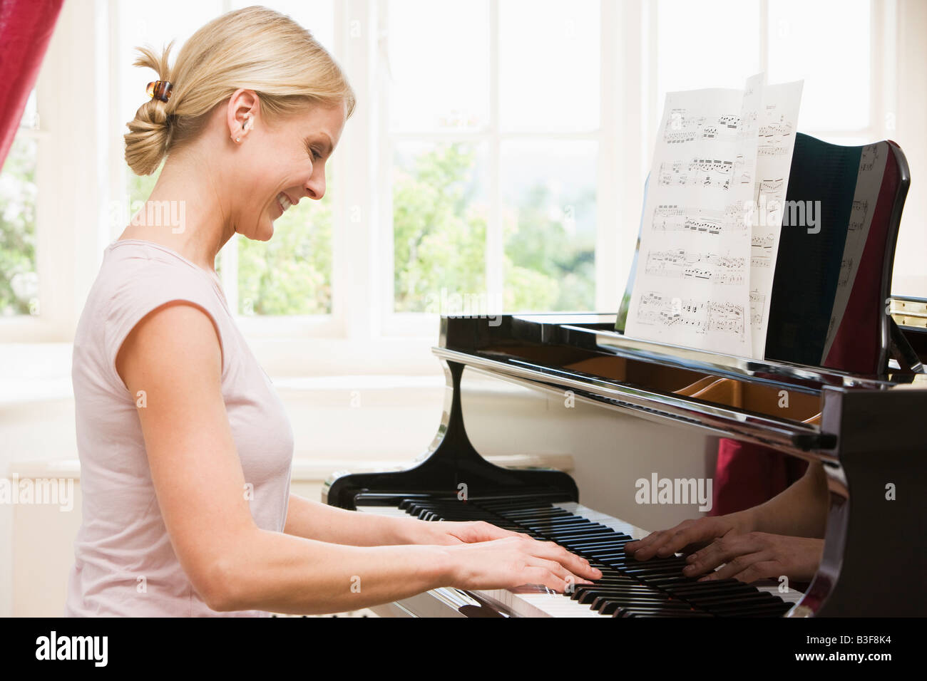 Woman playing piano and smiling Stock Photo - Alamy