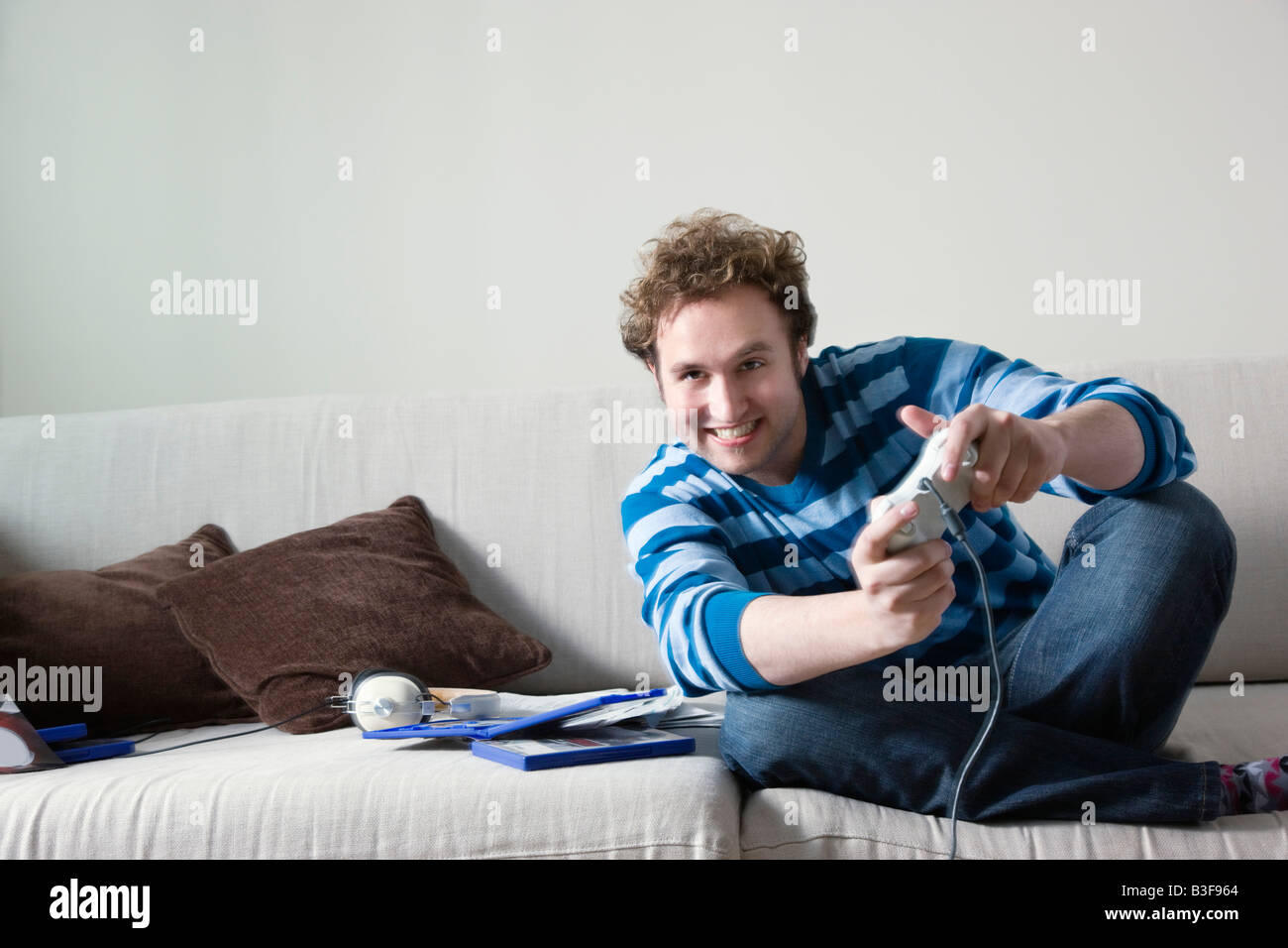 Man using computer game controls sitting on sofa Stock Photo - Alamy