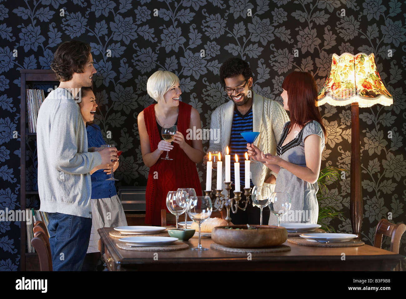 Group of people laughing, standing by dining table Stock Photo - Alamy