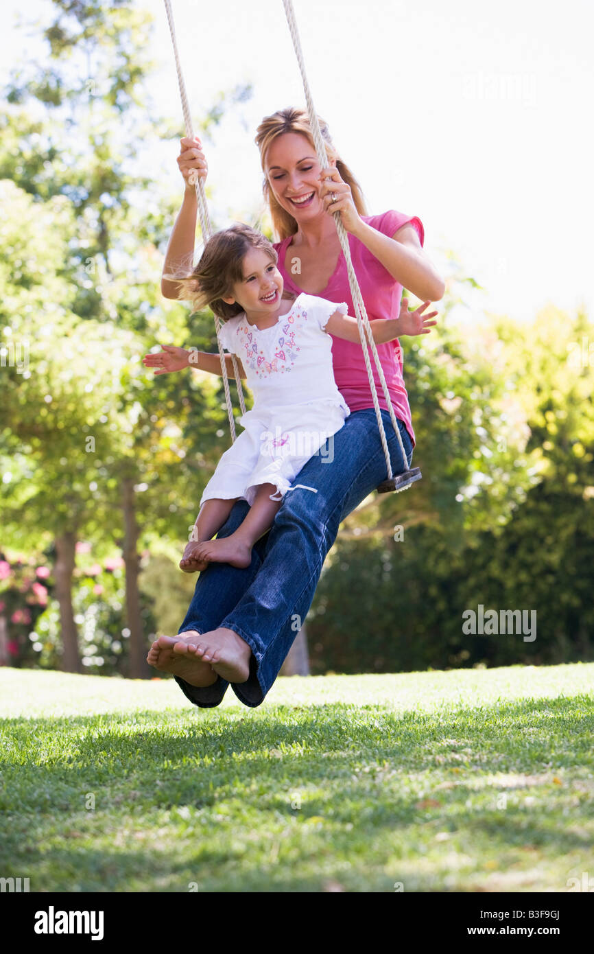 Woman and young girl outdoors on tree swing smiling Stock Photo - Alamy
