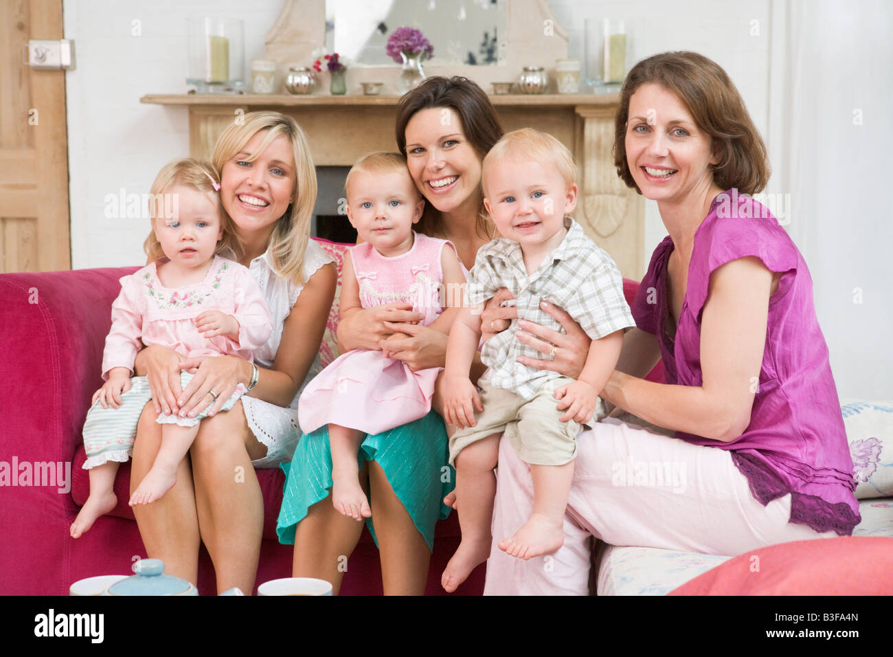 Three mothers in living room with babies smiling Stock Photo - Alamy