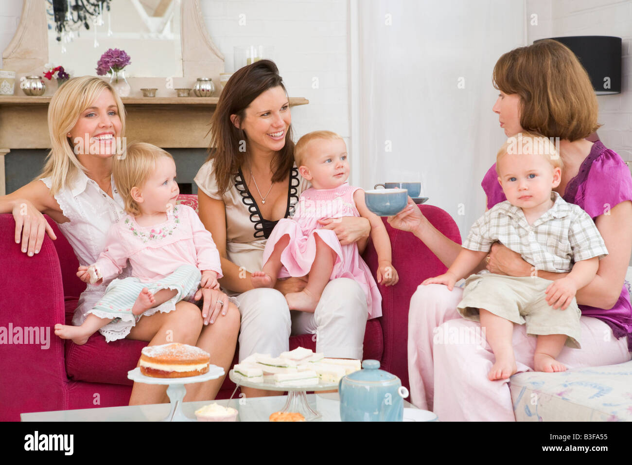 Three mothers in living room with babies and coffee smiling Stock Photo ...