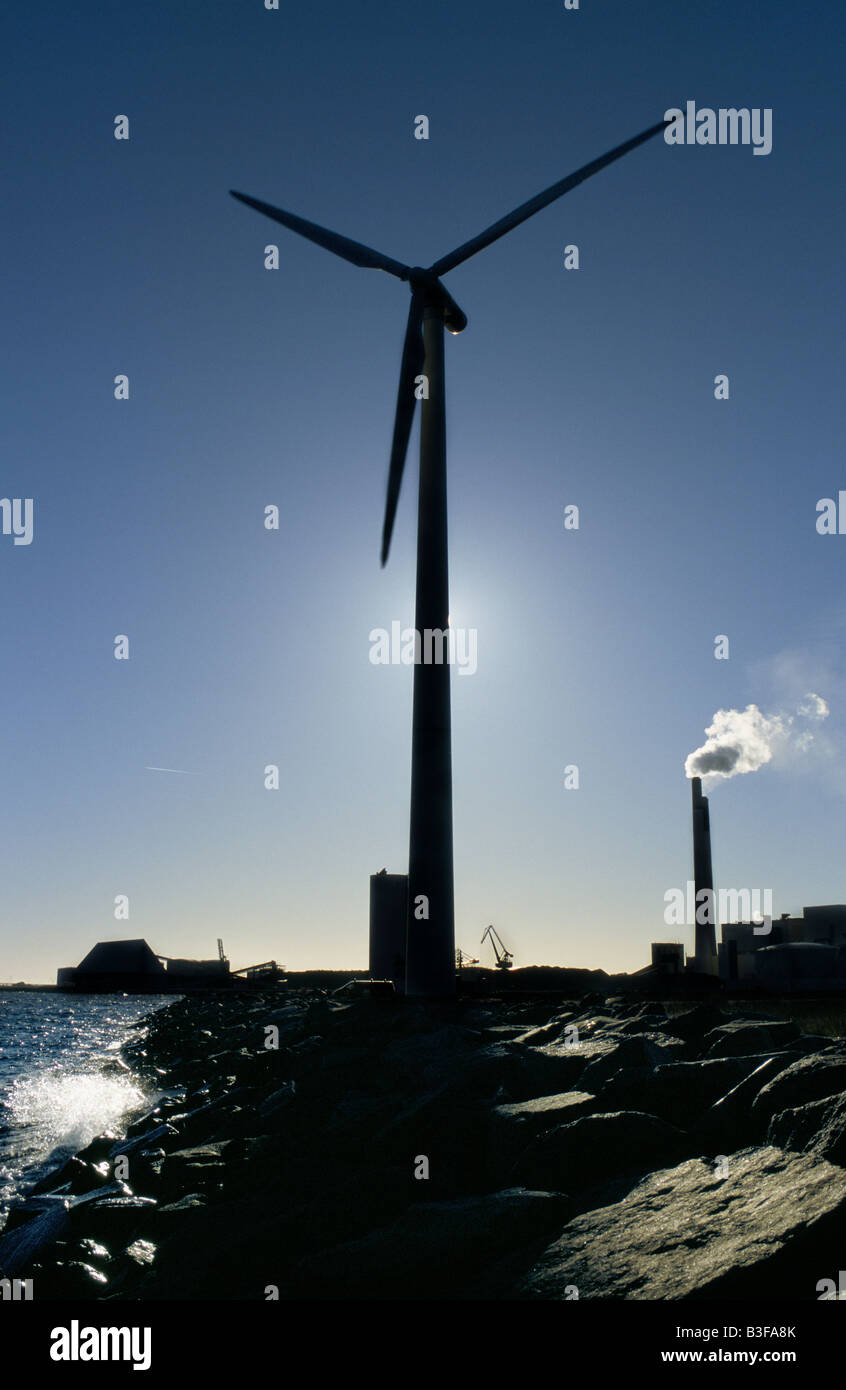 Wind turbine with a smoking chimney in the distance Stock Photo - Alamy