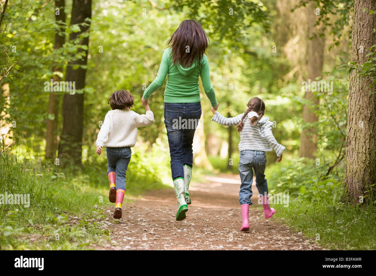 Mother and daughters skipping on path smiling Stock Photo - Alamy