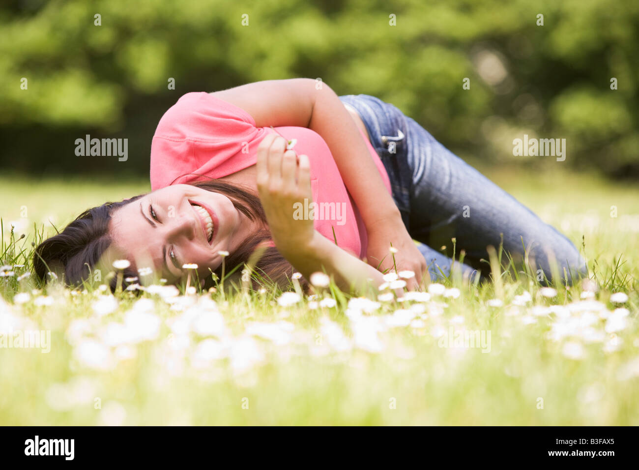 Woman lying outdoors with flower smiling Stock Photo - Alamy