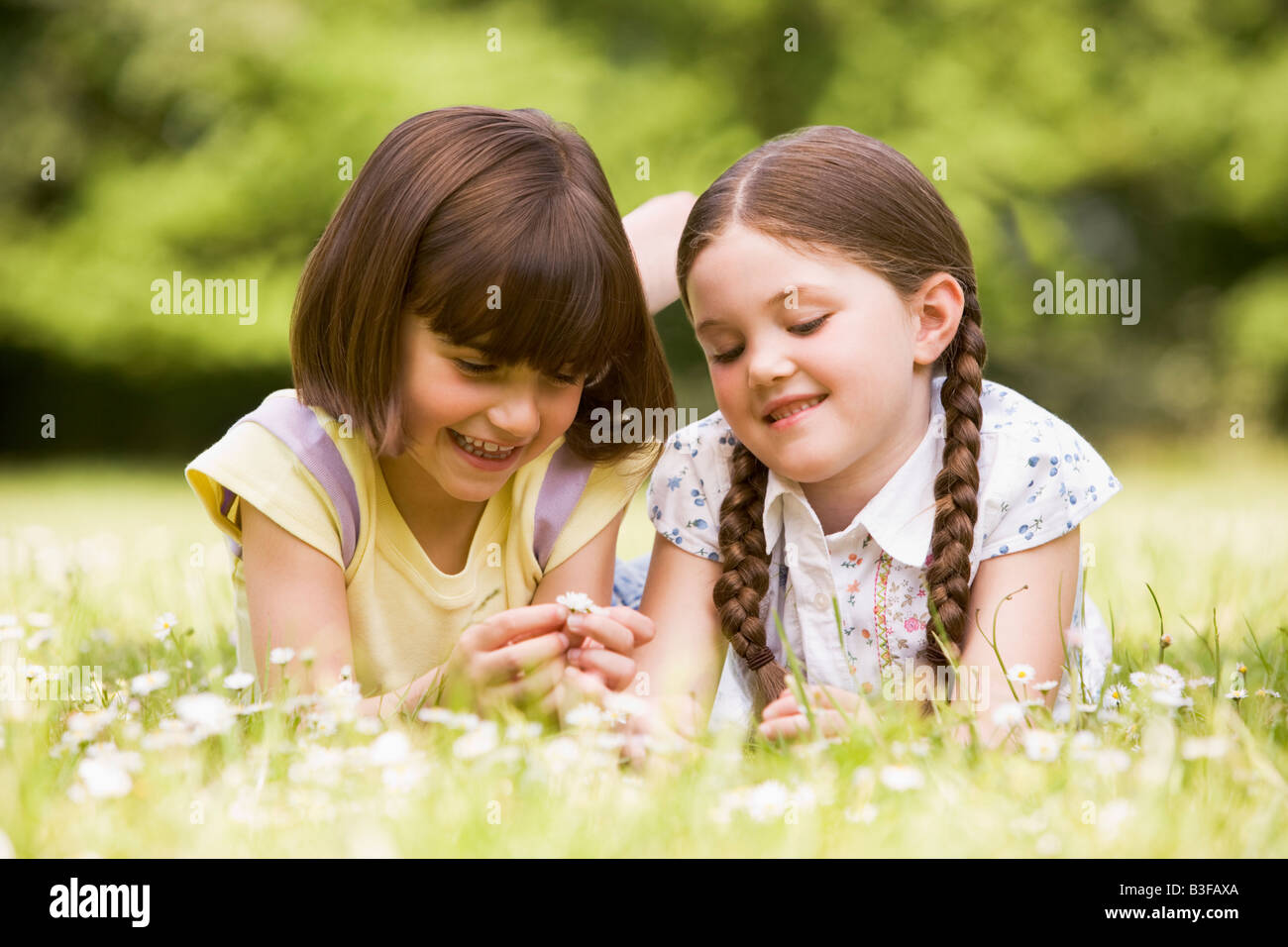 Two sisters lying outdoors with flower smiling Stock Photo - Alamy