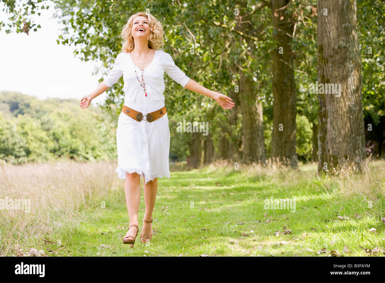 Woman walking on path smiling Stock Photo - Alamy