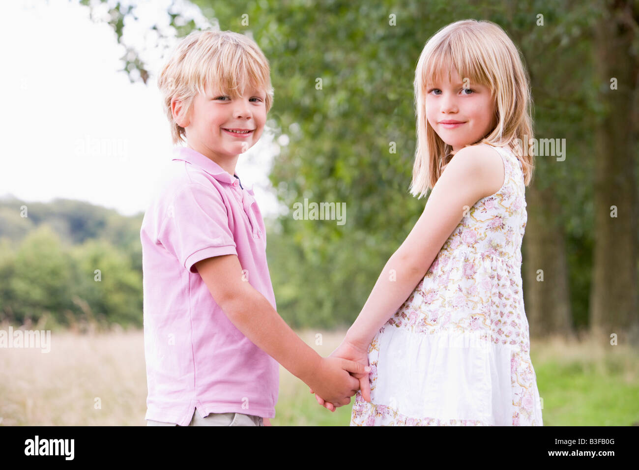 Two young children standing outdoors holding hands smiling Stock Photo ...