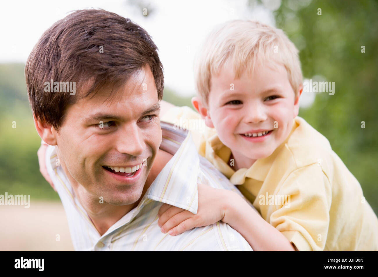 Father giving son piggyback ride outdoors smiling Stock Photo - Alamy