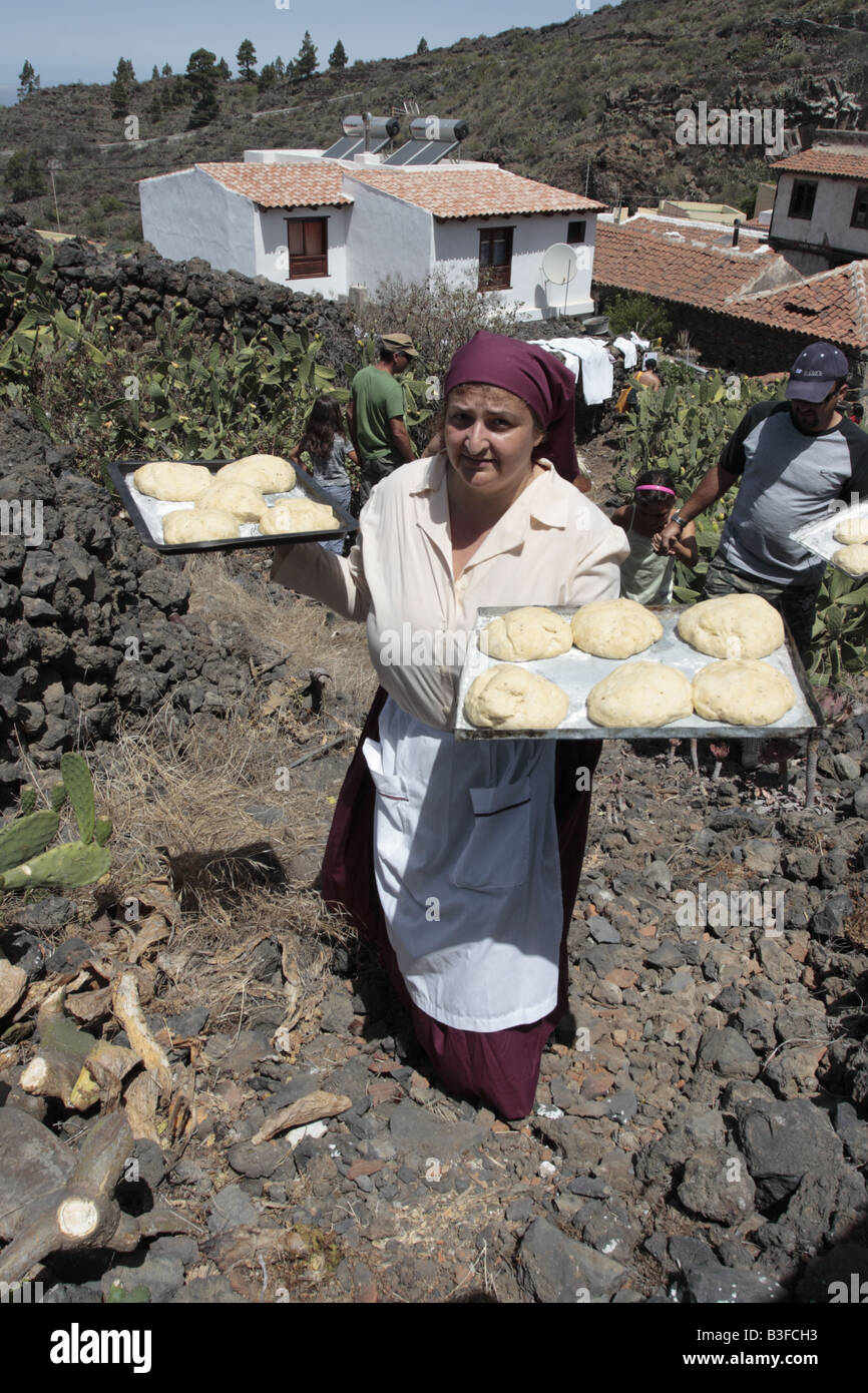 A woman carrying trays of dough ready to be placed in a communal bread ...