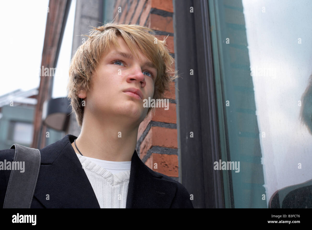 Teenage boy standing by window in street, low angle Stock Photo - Alamy