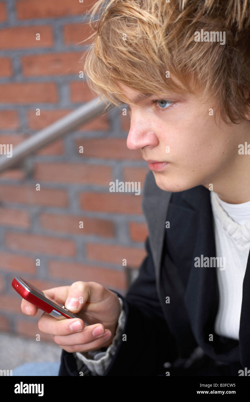 Teenage boy holding mobile phone, looking away Stock Photo - Alamy