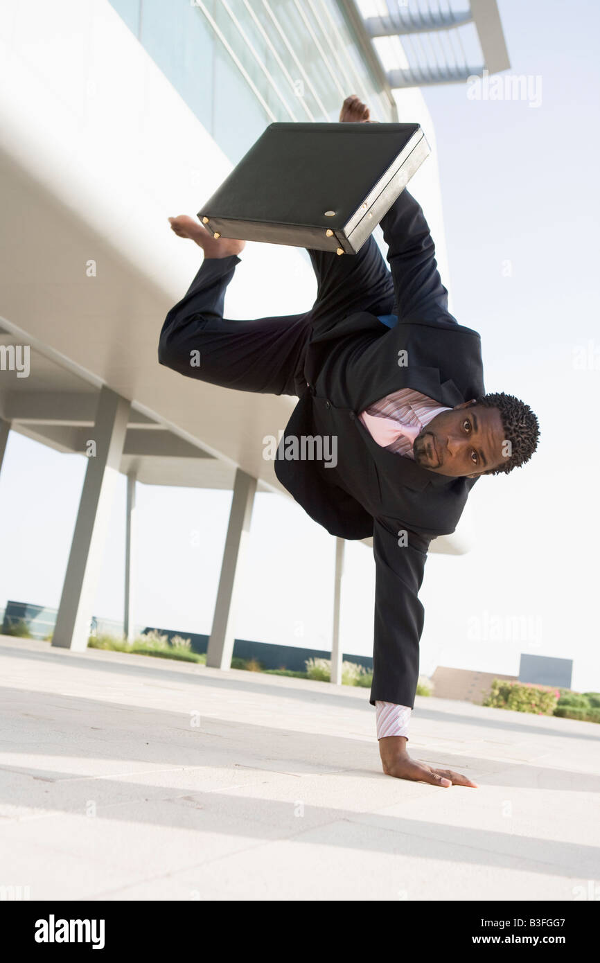 Businessman outdoors by building standing on one hand Stock Photo - Alamy