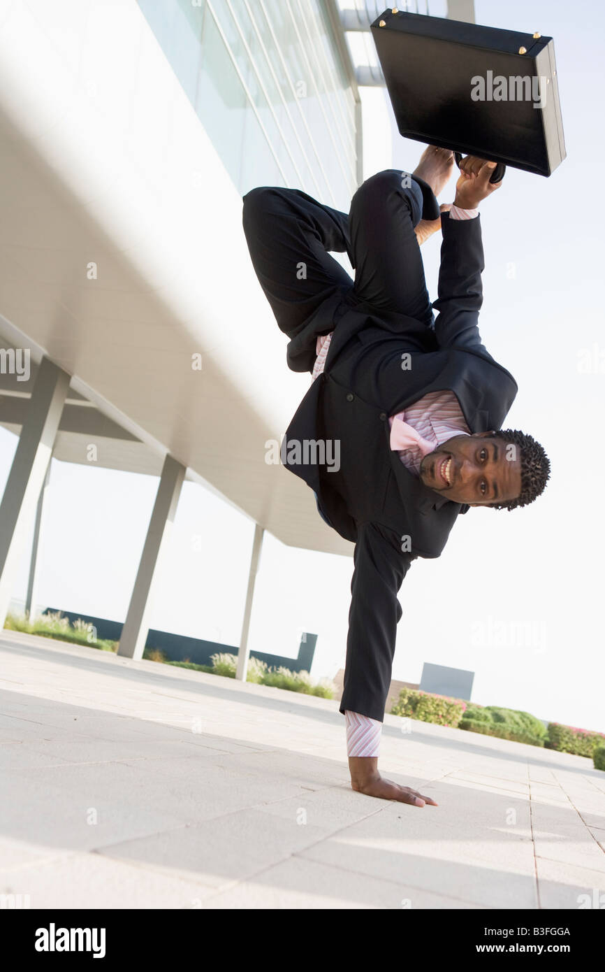 Businessman outdoors by building standing on one hand smiling Stock ...