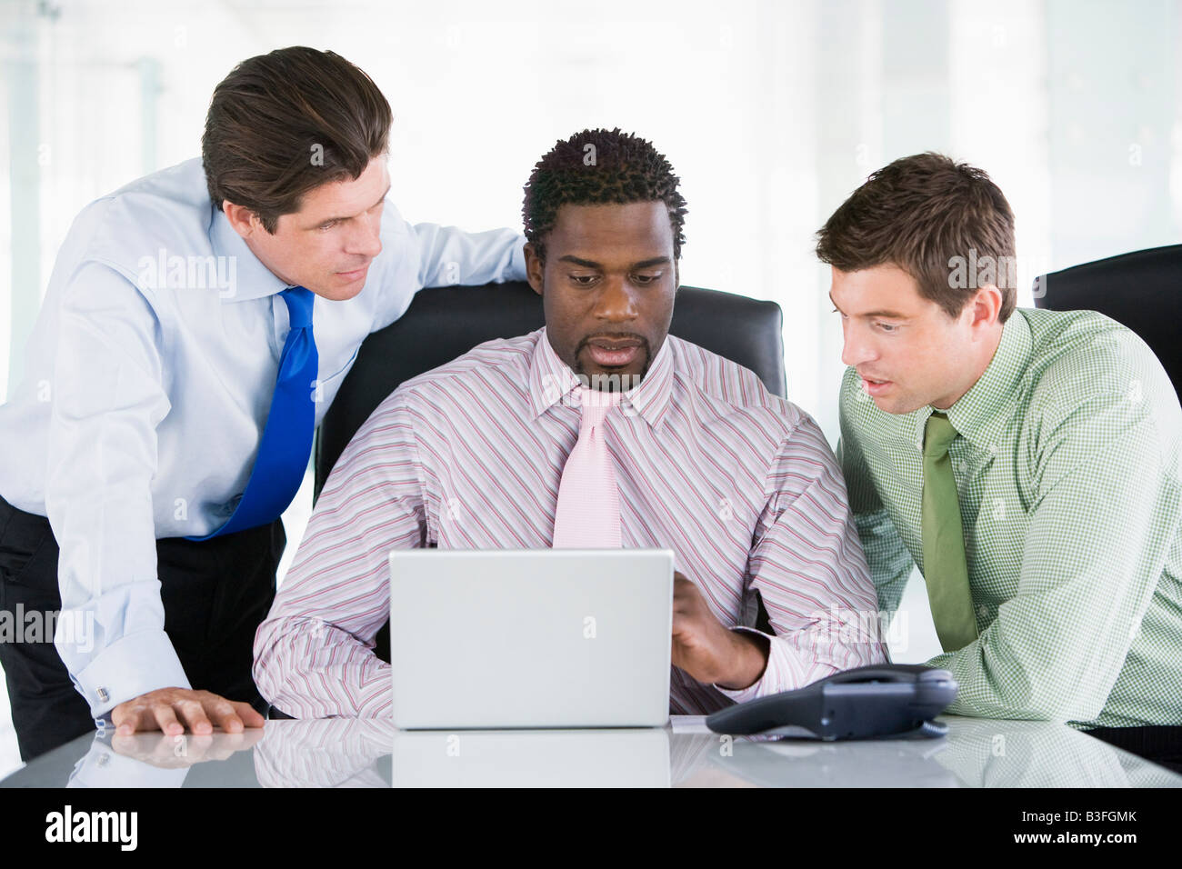 Three businessmen in a boardroom looking at laptop Stock Photo - Alamy