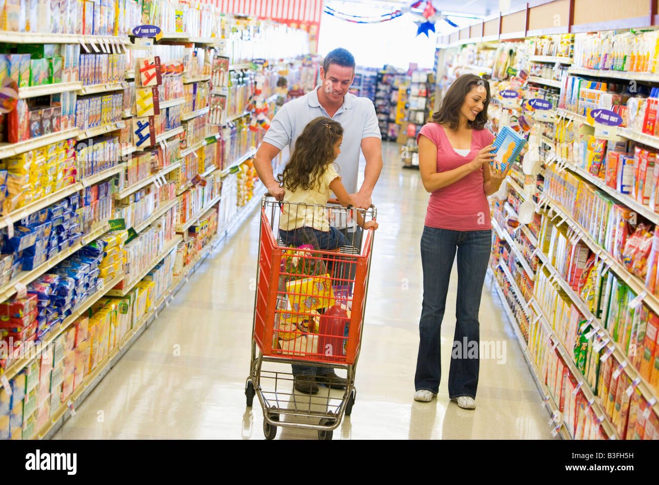 Mother and father with young daughter shopping at the grocery store ...