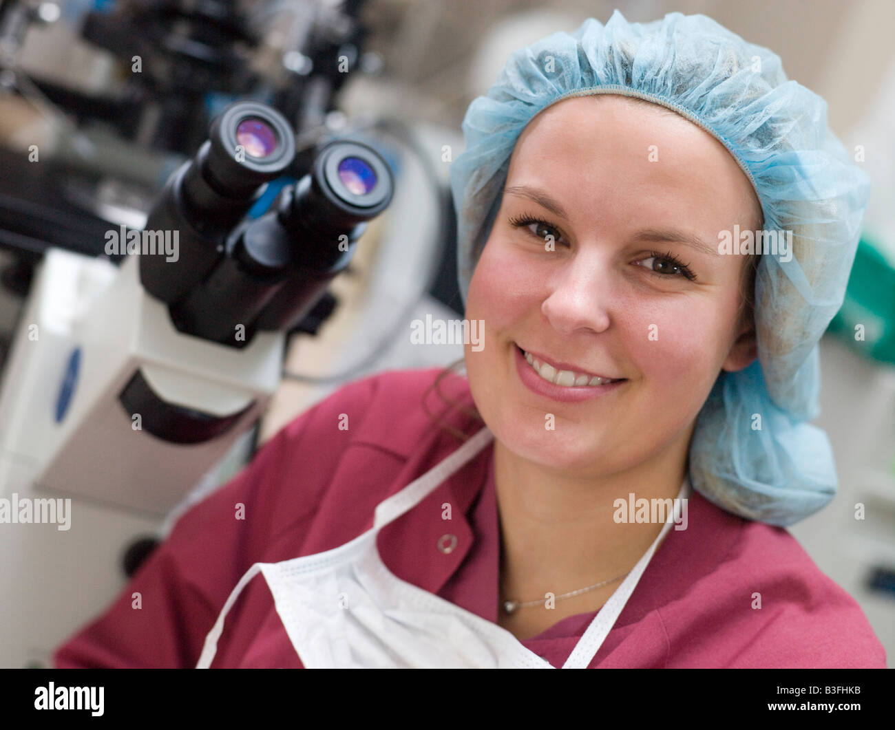 Embryologist sitting by microscope smiling (selective focus Stock Photo ...