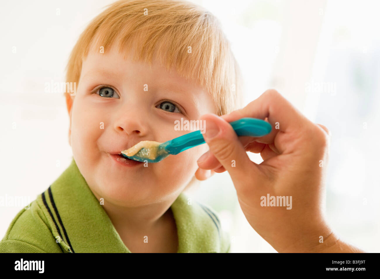 Mother feeding young boy baby food Stock Photo - Alamy