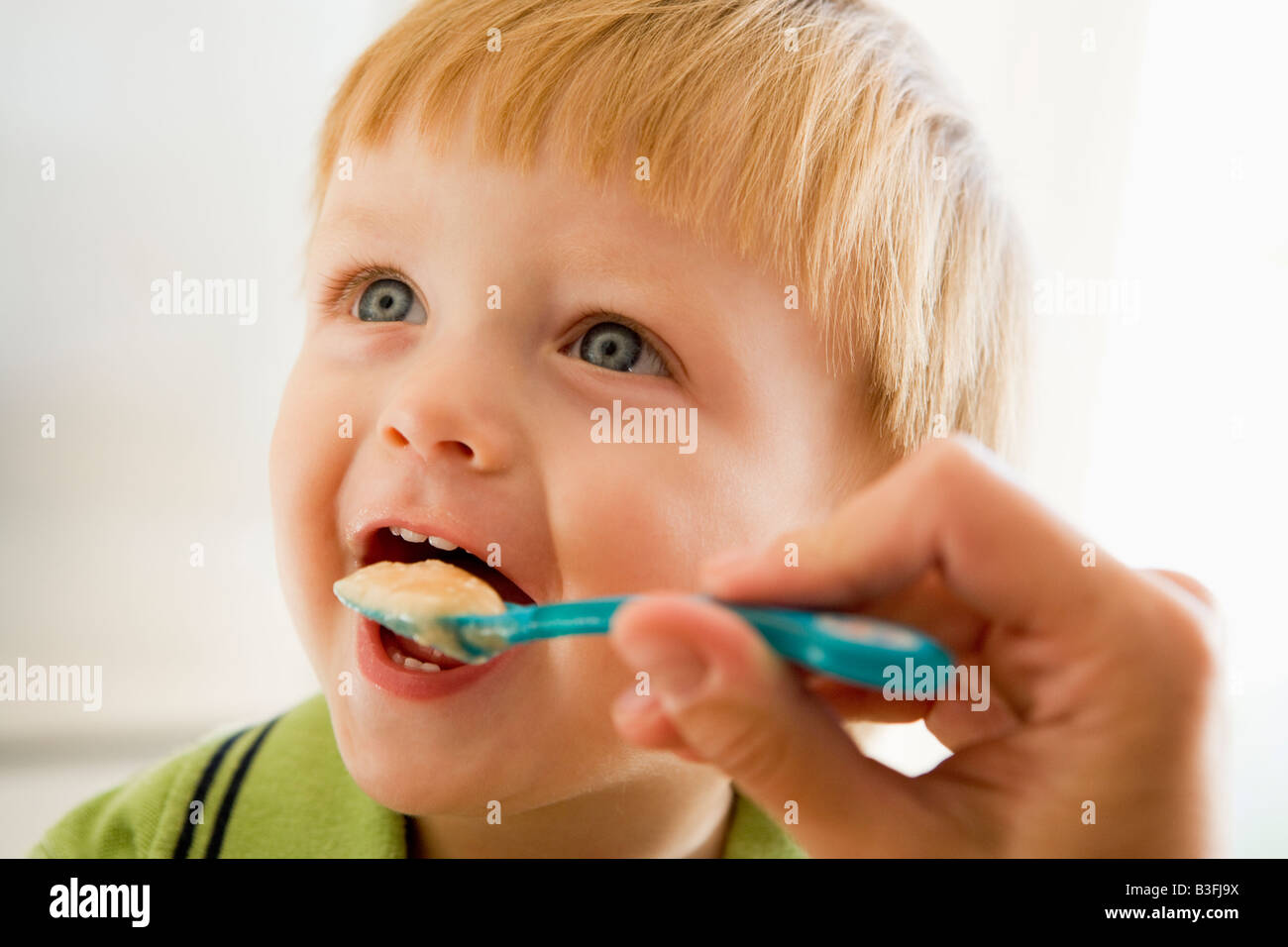 Mother feeding young boy baby food Stock Photo - Alamy