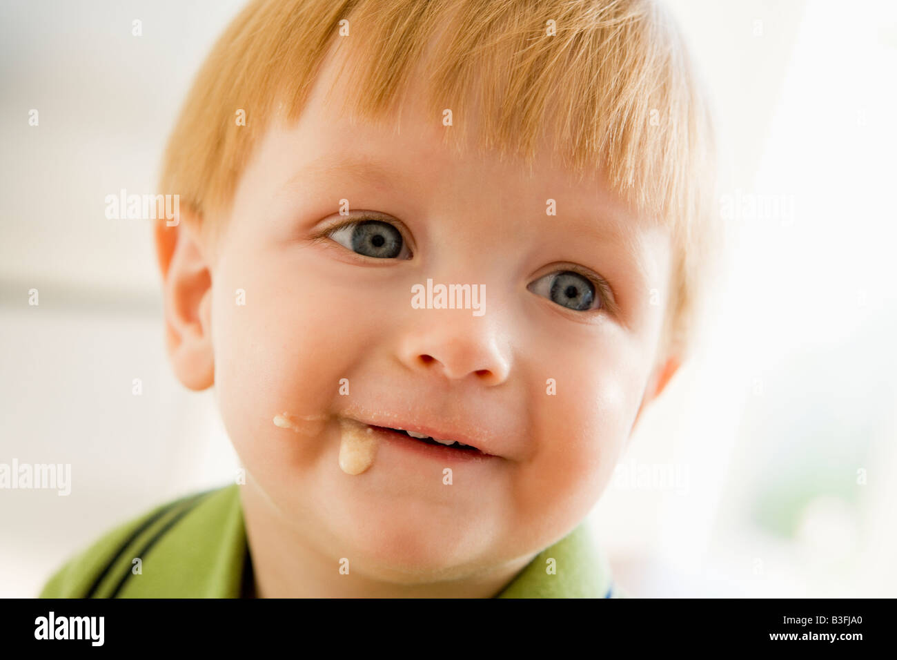 Young boy eating baby food with mess on face Stock Photo - Alamy