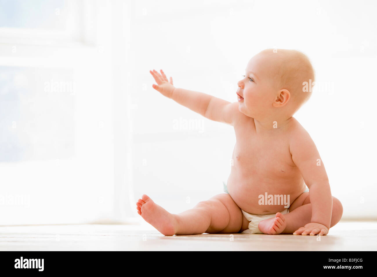 Baby sitting indoors Stock Photo - Alamy