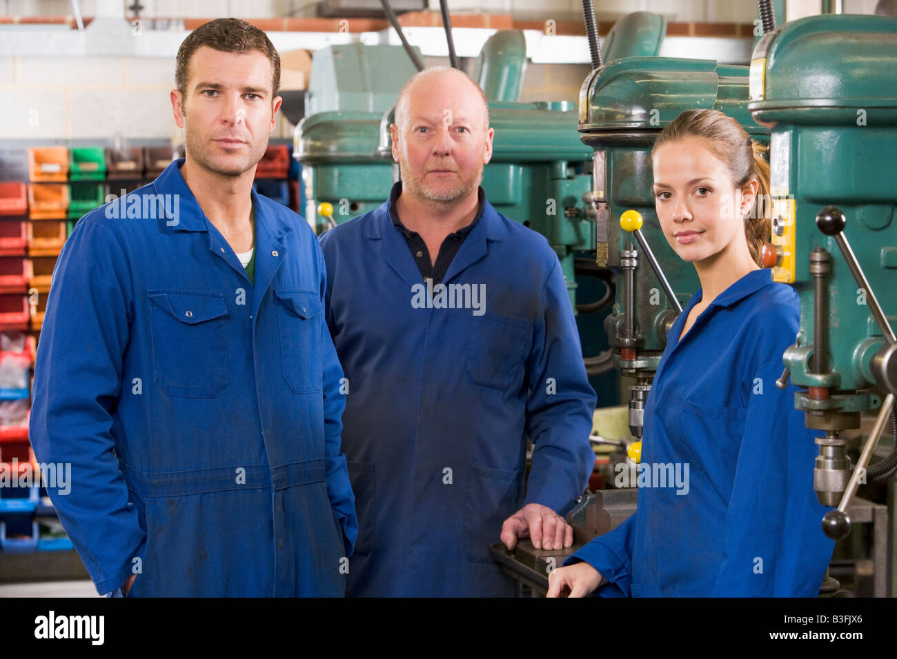 Three machinists in workspace by machine talking Stock Photo - Alamy