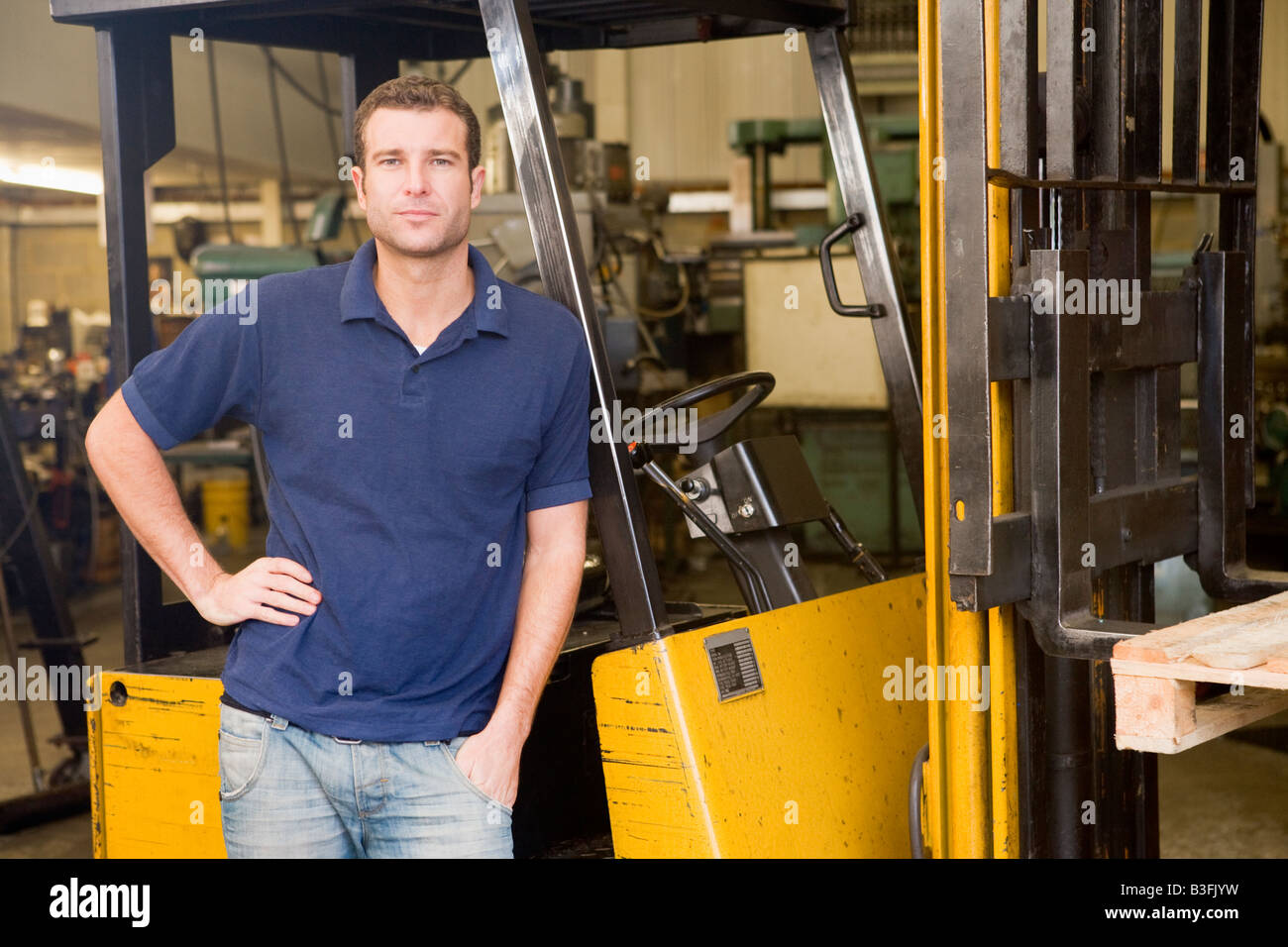 Warehouse worker standing by forklift Stock Photo - Alamy