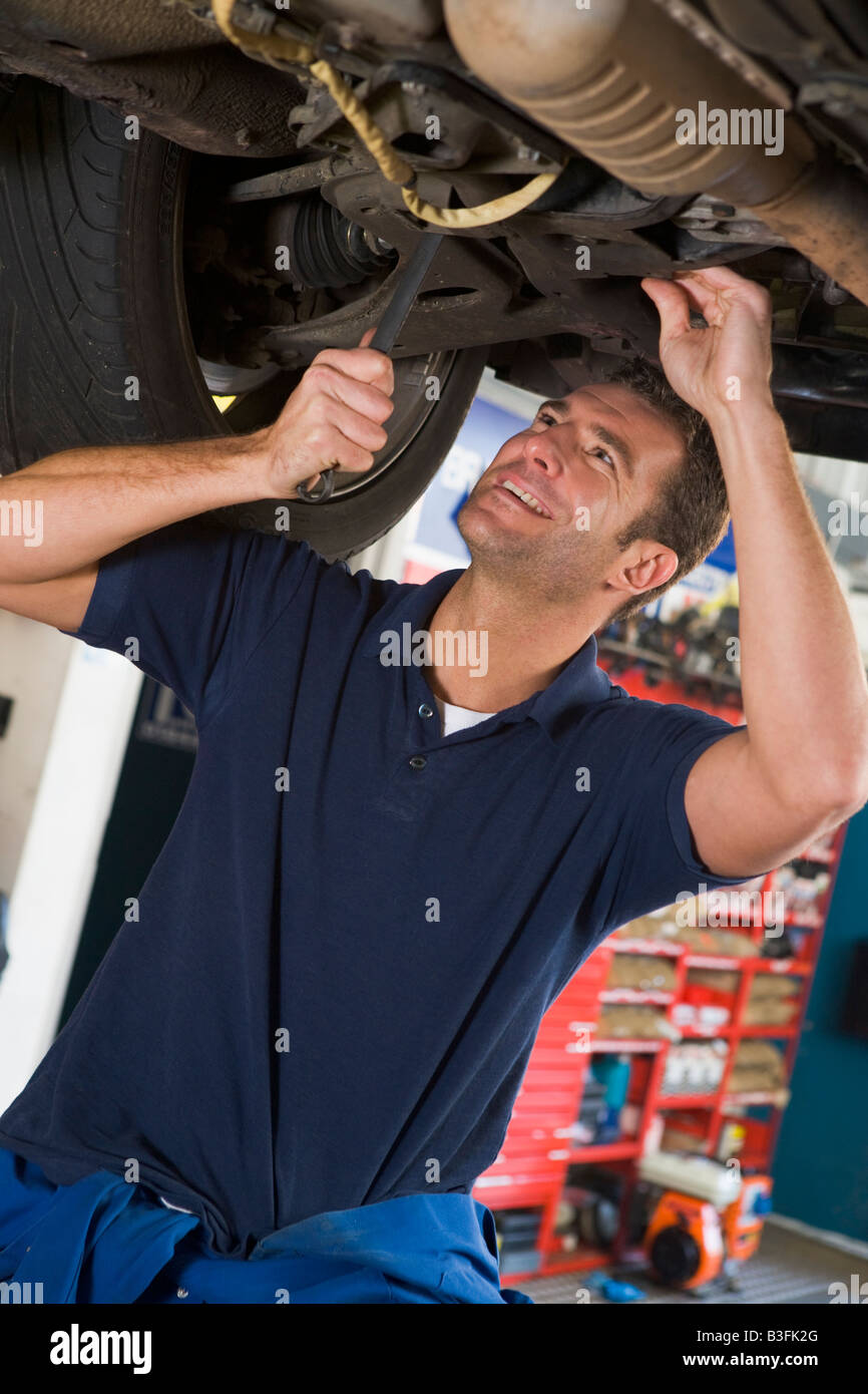 Mechanic working under car smiling Stock Photo - Alamy