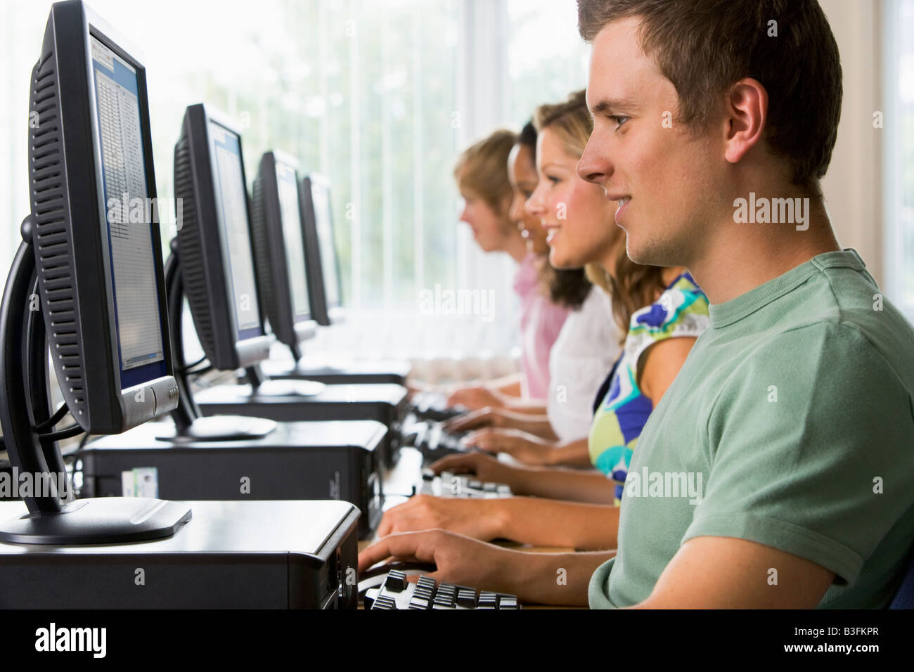 Four people sitting at computer terminals (depth of field/high key ...