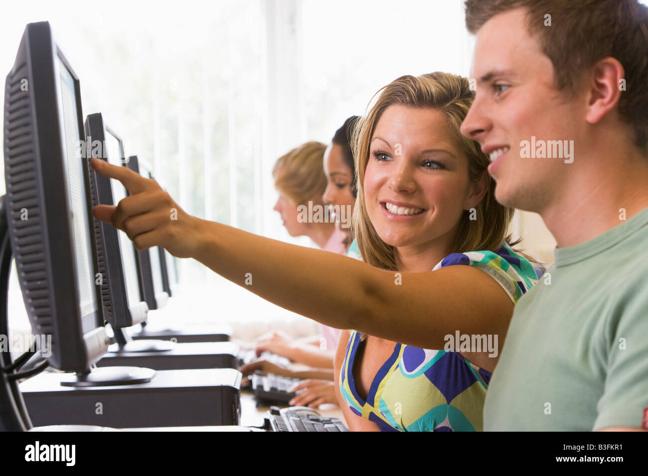 Four people sitting at computer terminals (depth of field/high key ...