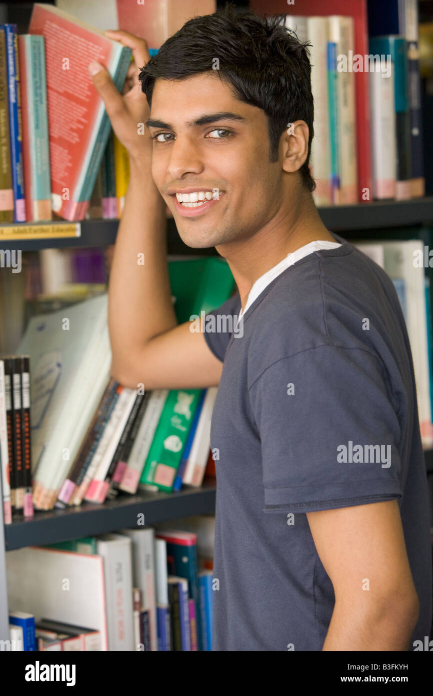Man in library pulling book off shelf Stock Photo - Alamy