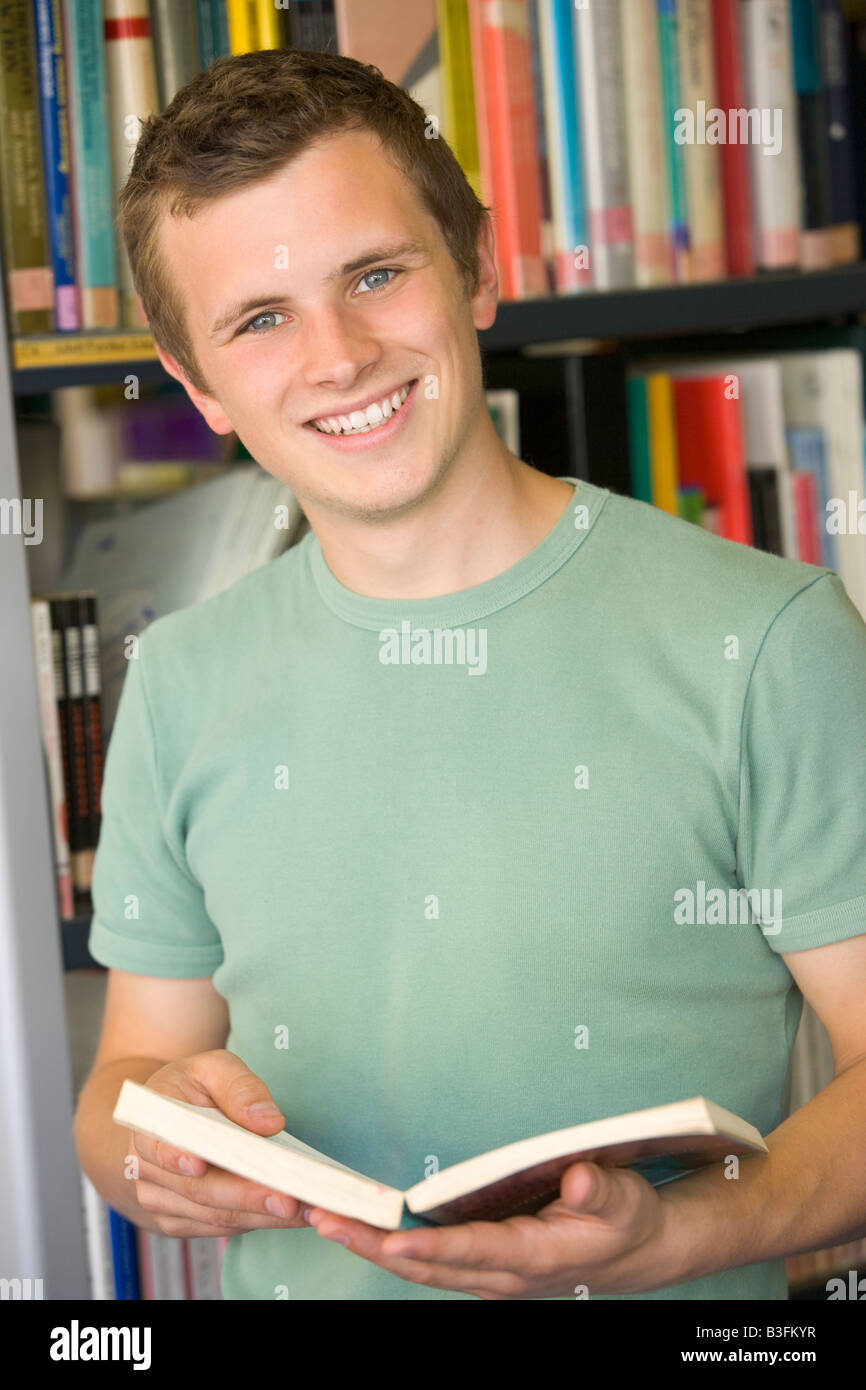 Man in library holding book Stock Photo - Alamy