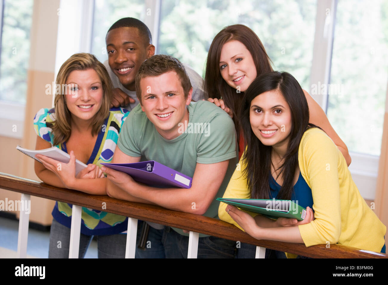 Five students in corridor leaning on railing with notebooks Stock Photo ...