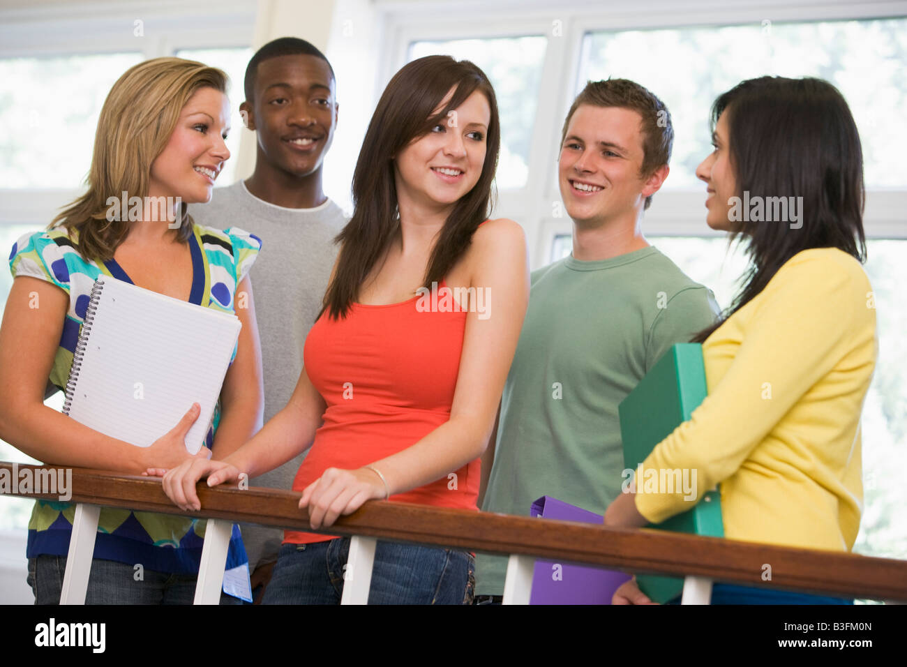 Five students in corridor leaning on railing with notebooks Stock Photo ...