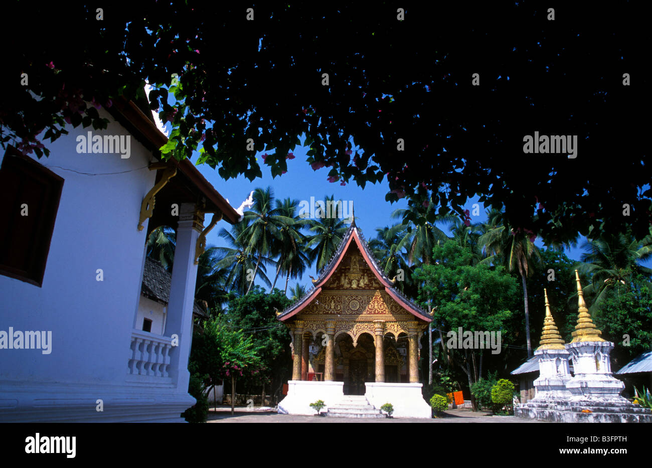The tranquil grounds of Wat Pha Phai are surrounded by shrubbery and ...