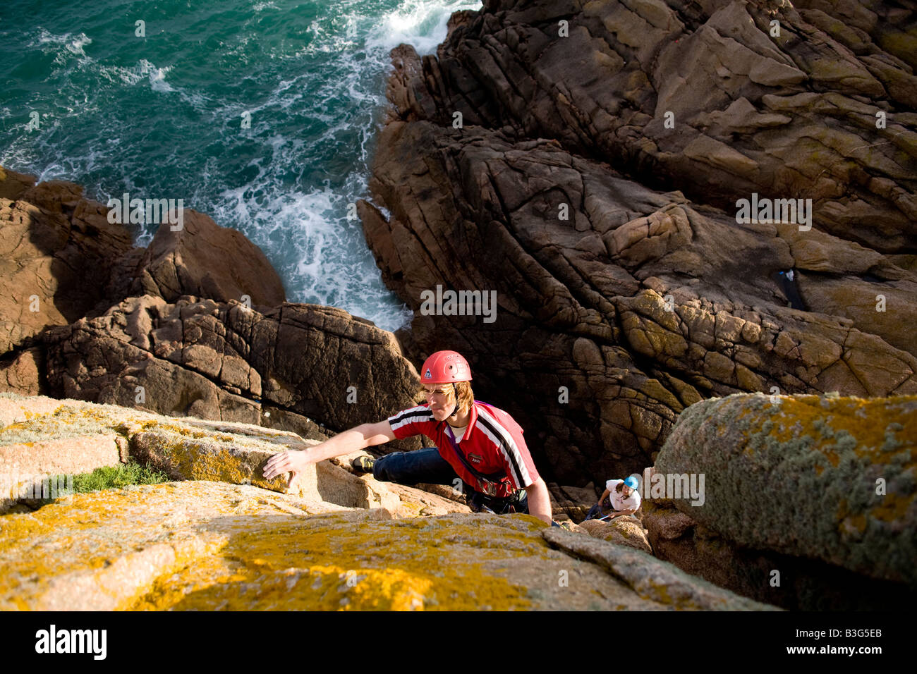 1 man rock climbing up sea cliffs Stock Photo - Alamy
