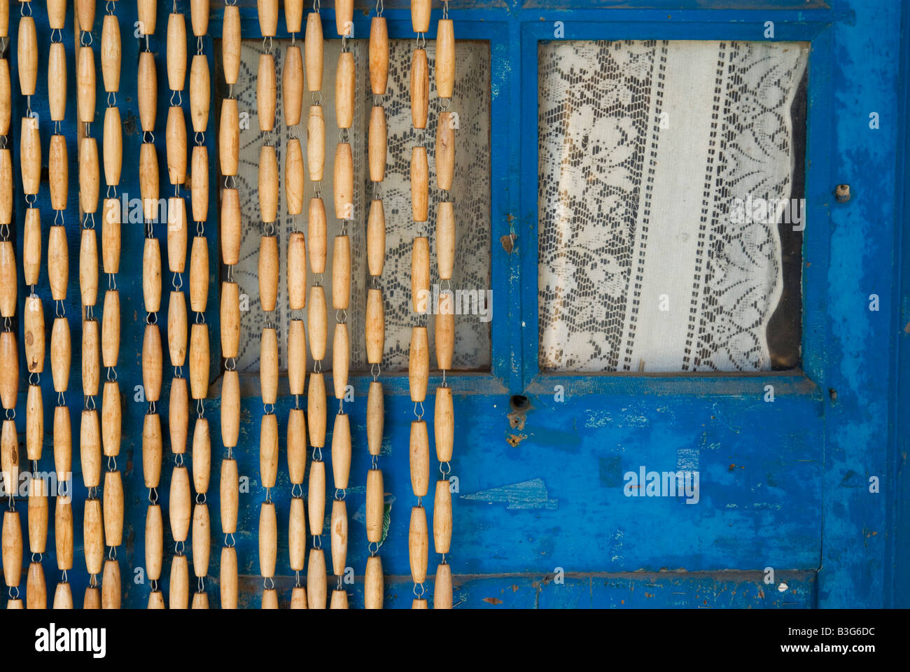 Blue door with lace curtain and beaded screen Stock Photo - Alamy