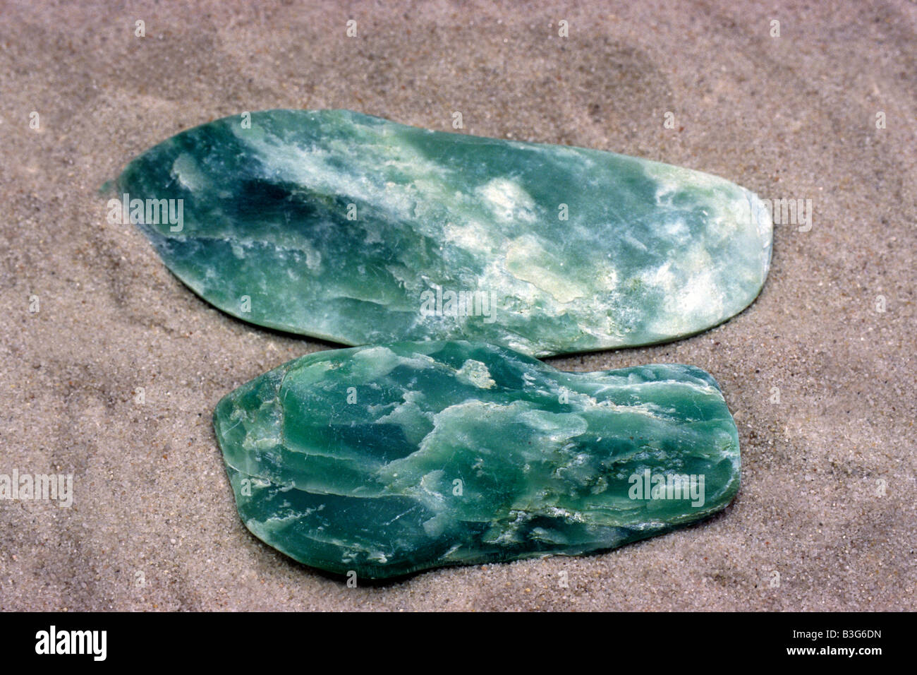 Jade, Jadeit, two pieces on sand, studio picture Stock Photo - Alamy