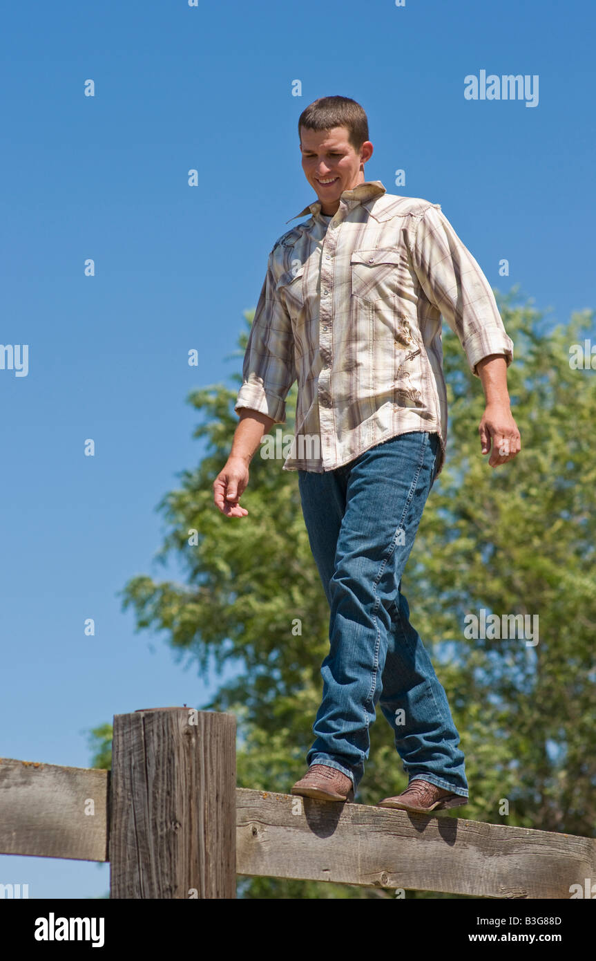 A man walks on a fence on a farm Stock Photo - Alamy
