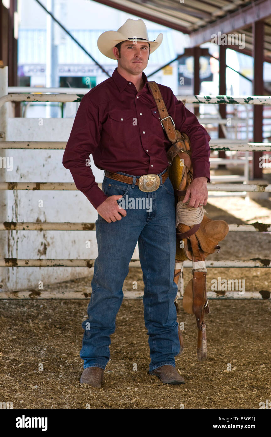 Idaho. A cowboy stands with his saddle in a corral at a rodeo Stock ...