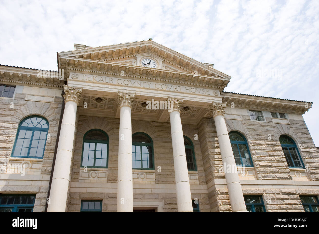 An old county courthouse of granite with columns under a cloudy sky ...