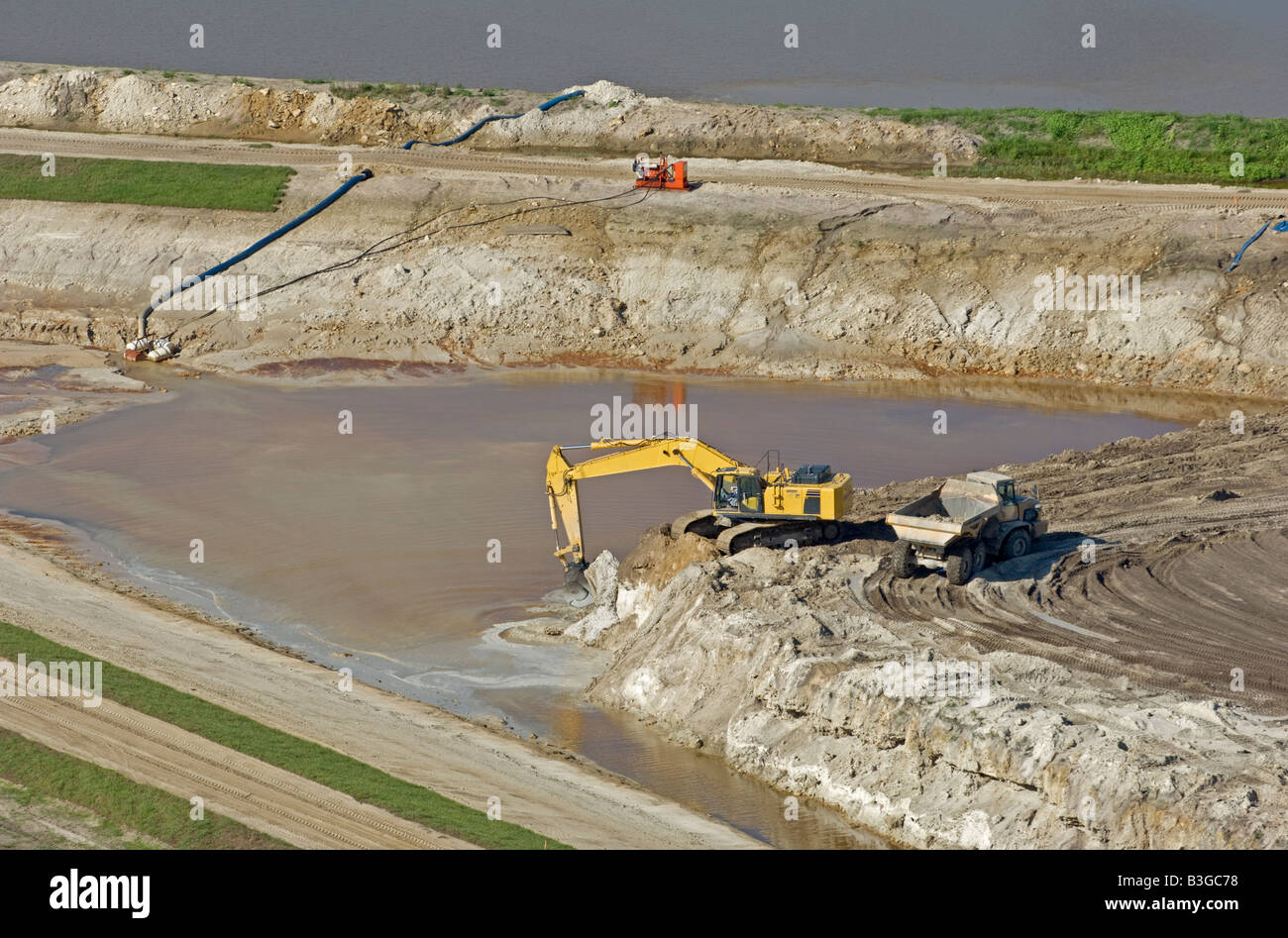 trackhoe and dump truck at work site moving earth construction project ...
