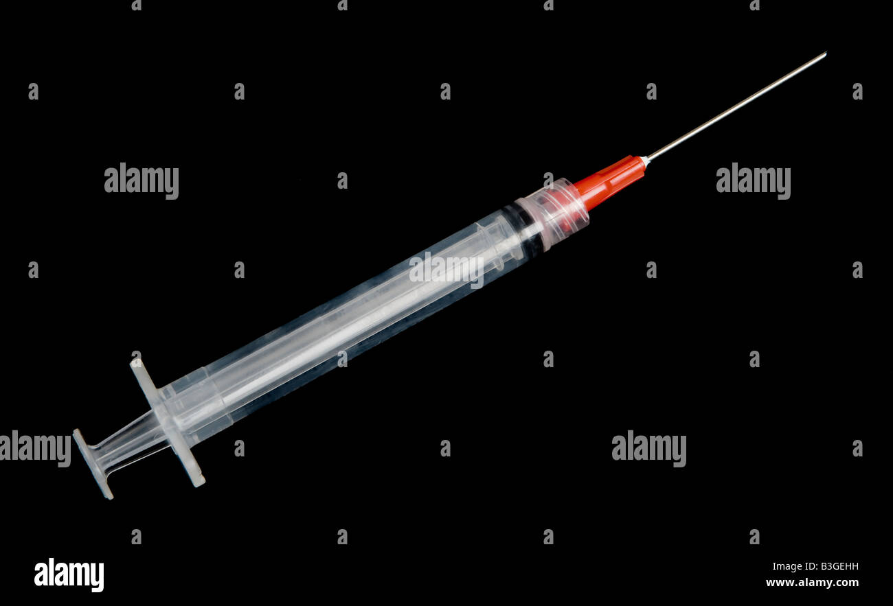 A medical syringe with exposed needle isolated on a black background ...