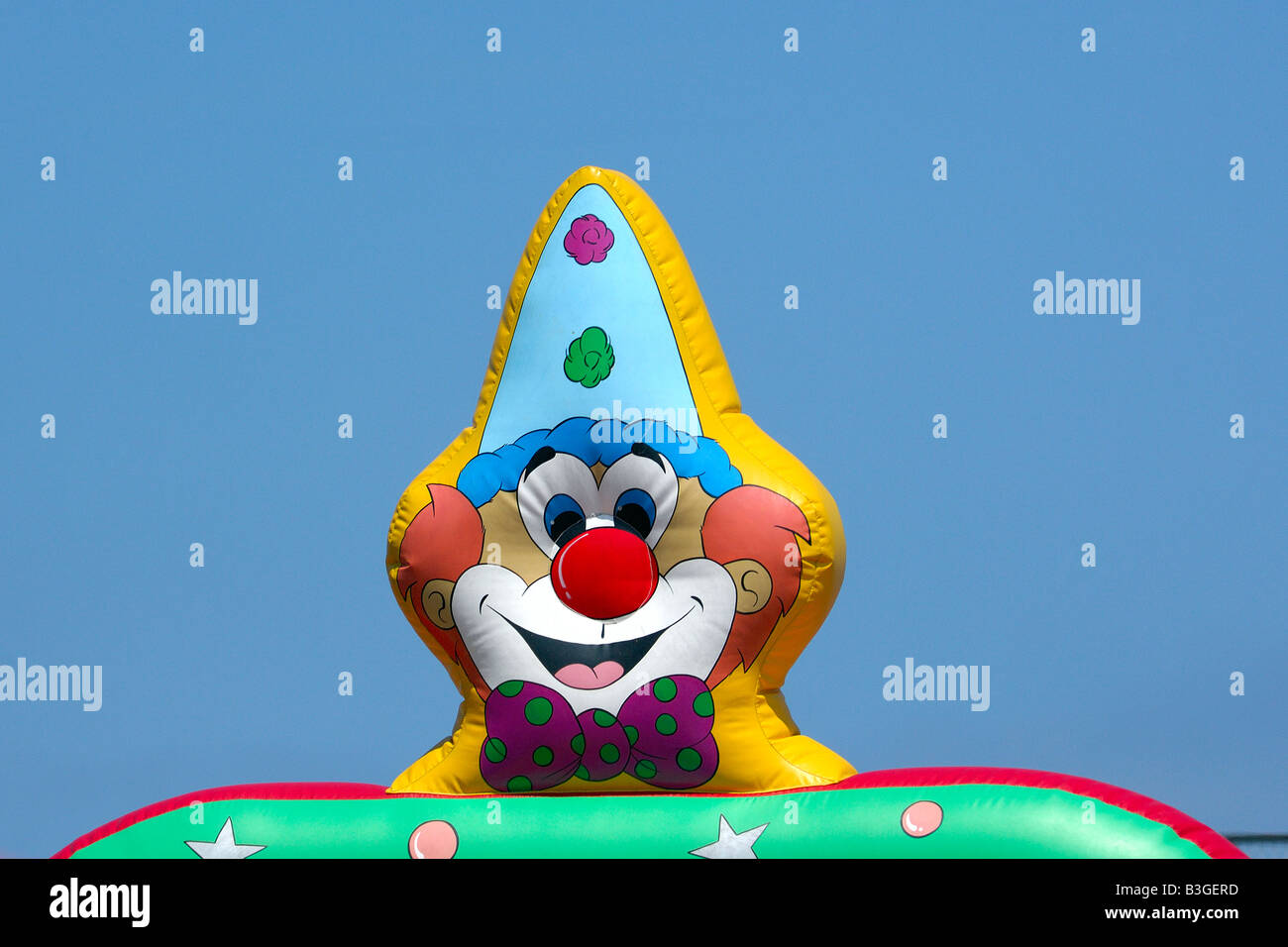 Colourful clowns head on to of an inflatable bouncy castle at a ...