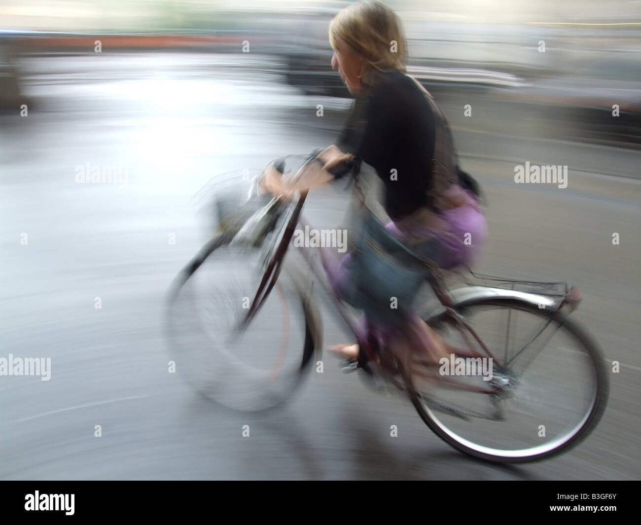 person riding fast bike on street in rain in town Stock Photo - Alamy