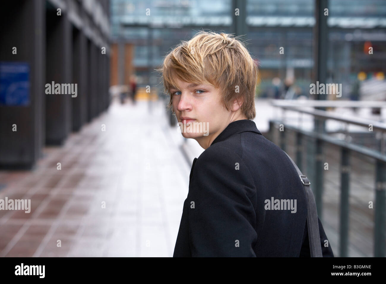 Teenage boy looking back over his shoulder in city Stock Photo - Alamy